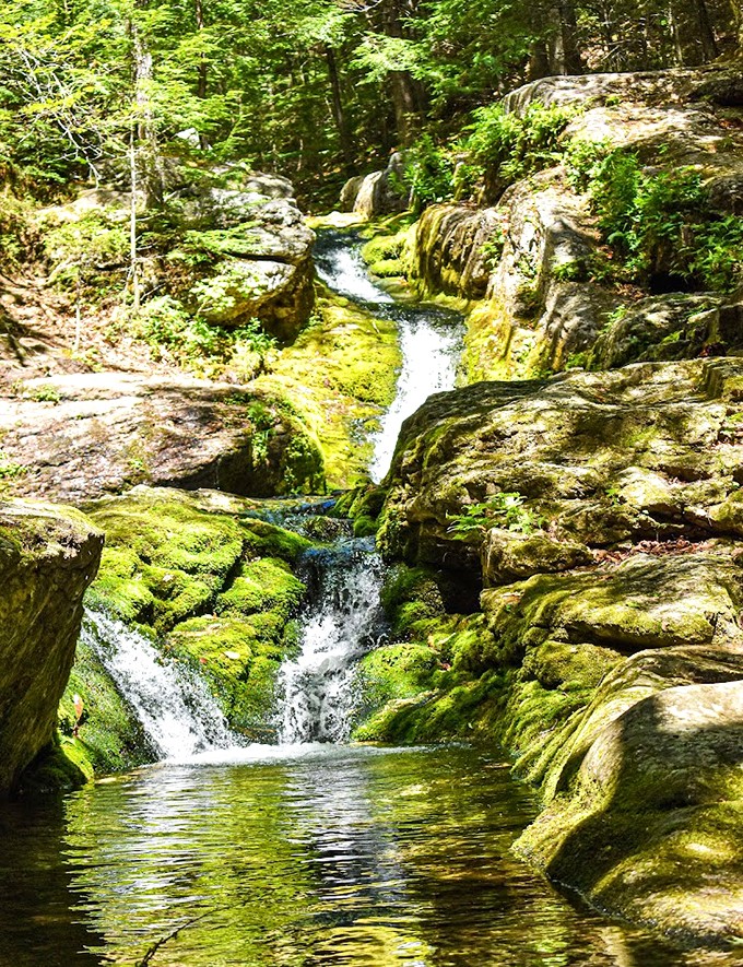 A gentle cascade tumbles over ancient rocks, creating nature's own meditation soundtrack in this peaceful corner of Maine.