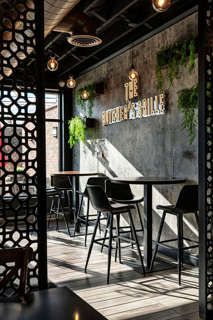 Modern geometric screens and hanging plants create an atmosphere that's equal parts urban oasis and neighborhood gem.