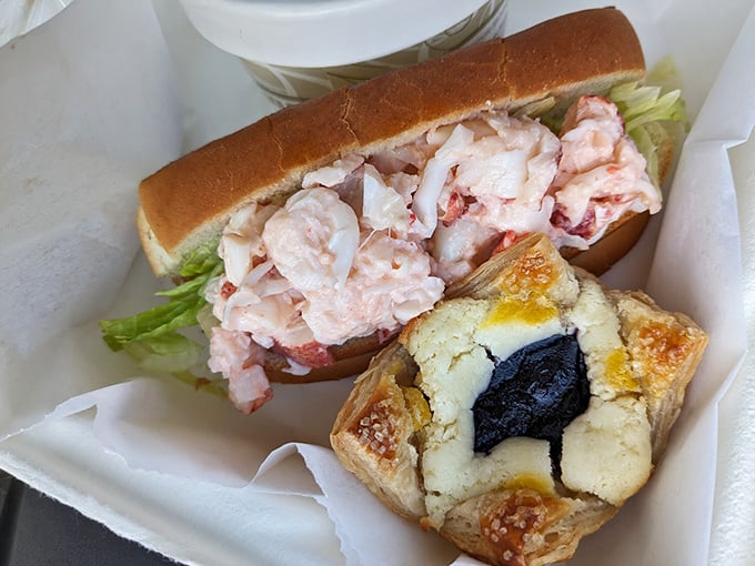 A classic Maine lobster roll in its purest form: sweet meat, light mayo, crisp lettuce, and a buttery roll, served with what appears to be a blueberry pastry. Photo credit: Mike Ryan