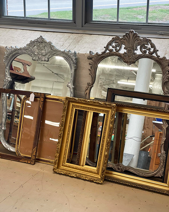 Ornate mirrors from bygone eras lean casually against the wall, each frame more elaborate than the last.