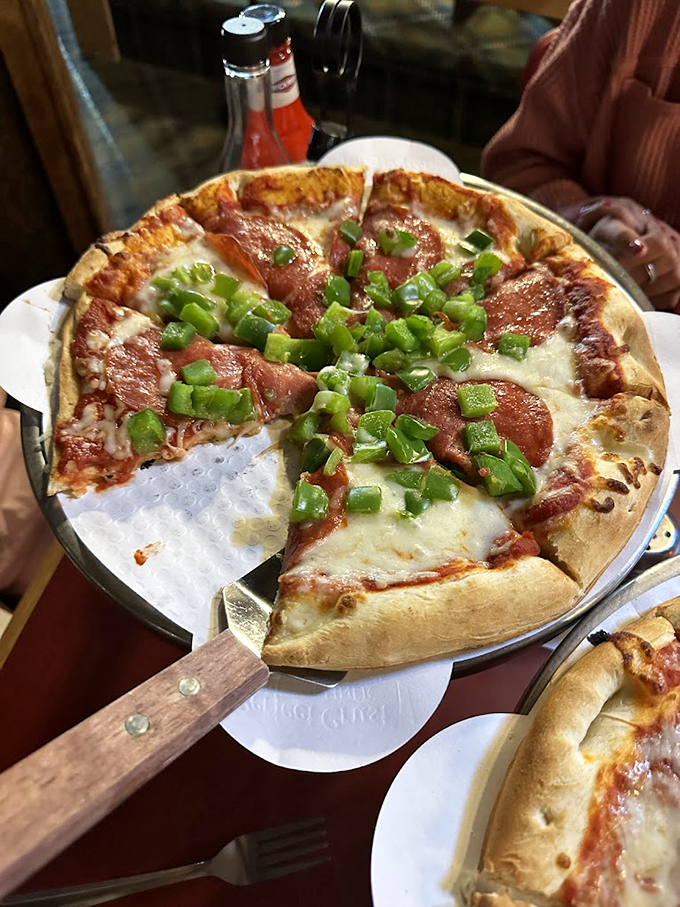 Green peppers dance across a canvas of melted cheese and pepperoni, proving great pizza exists even in fish country.