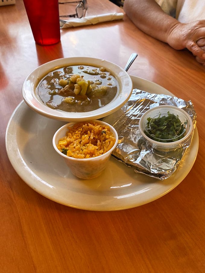 A hearty bowl of pozole comes with perfectly seasoned rice and fresh garnishes - comfort food that warms the soul.