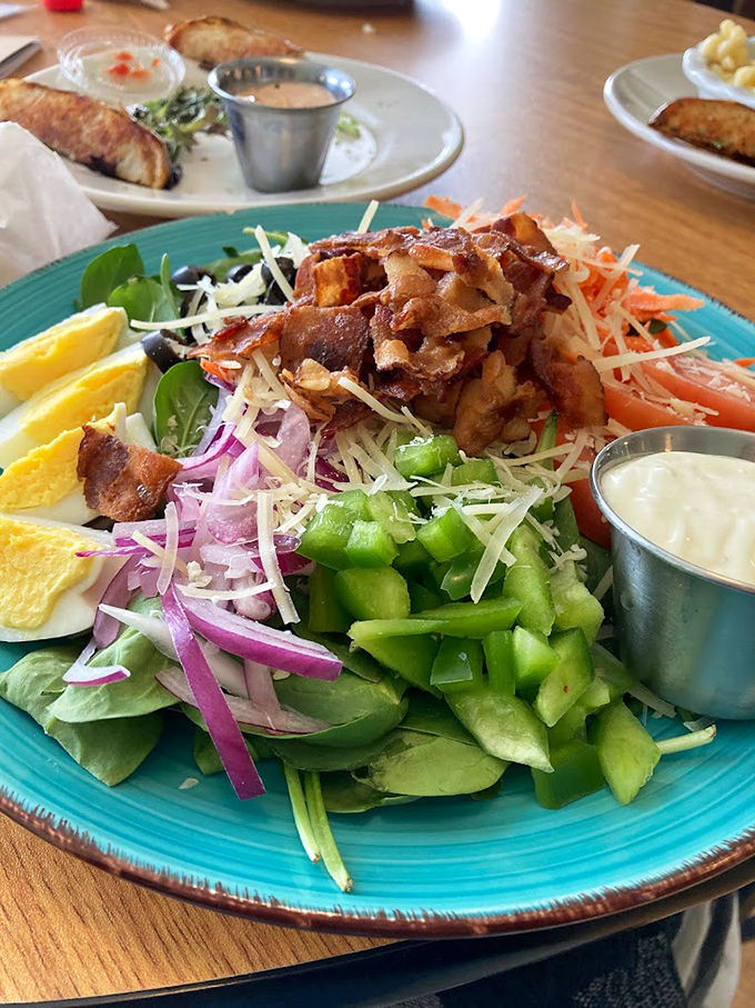 A garden party on a turquoise plate, where crisp vegetables dance with bacon that's dressed for success.