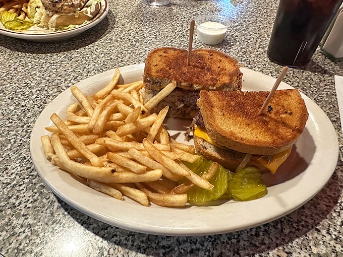 A sandwich stacked higher than your dad's stories about walking to school uphill both ways, with crispy fries standing guard. Photo credit: Alison Ortiz