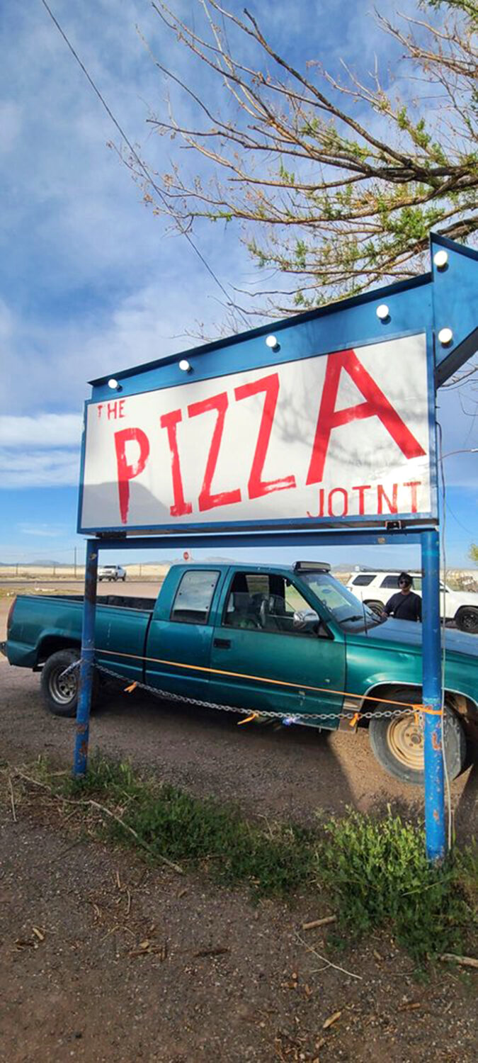 The bold blue-and-white sign stands tall against Arizona's endless sky, a beacon for hungry travelers seeking pizza paradise. 