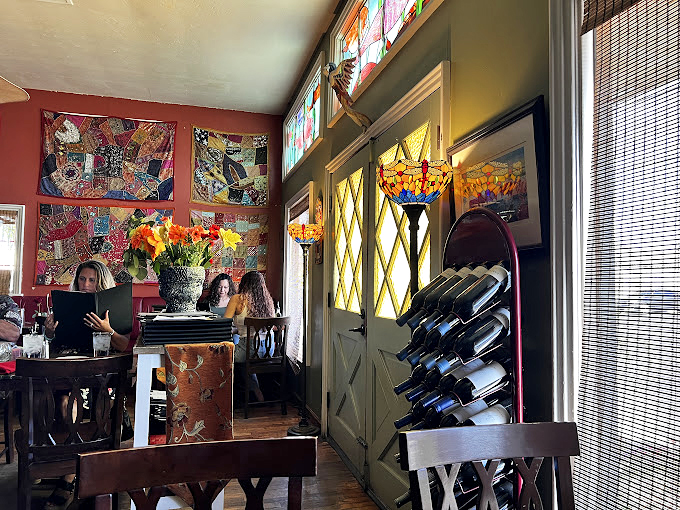 Stained glass windows cast rainbow shadows across the dining room, while wine bottles stand ready for their moment. 