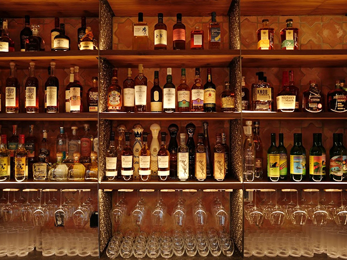 A carefully curated wall of spirits stands ready to complement your meal. From bourbon to wine, every bottle tells a story.