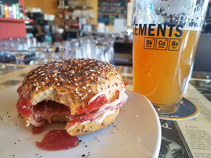The dynamic duo of sustenance: a hearty bagel sandwich and a crisp brew. It's like Batman and Robin, but for your taste buds.