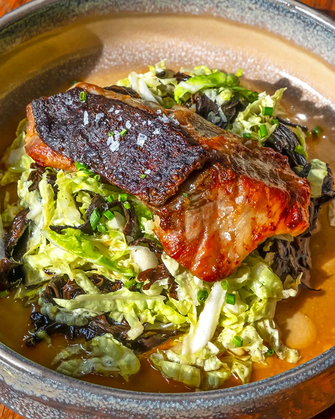 Crispy-skinned bluefish rests on a bed of fresh greens, proving sometimes the simplest preparations are the most elegant.