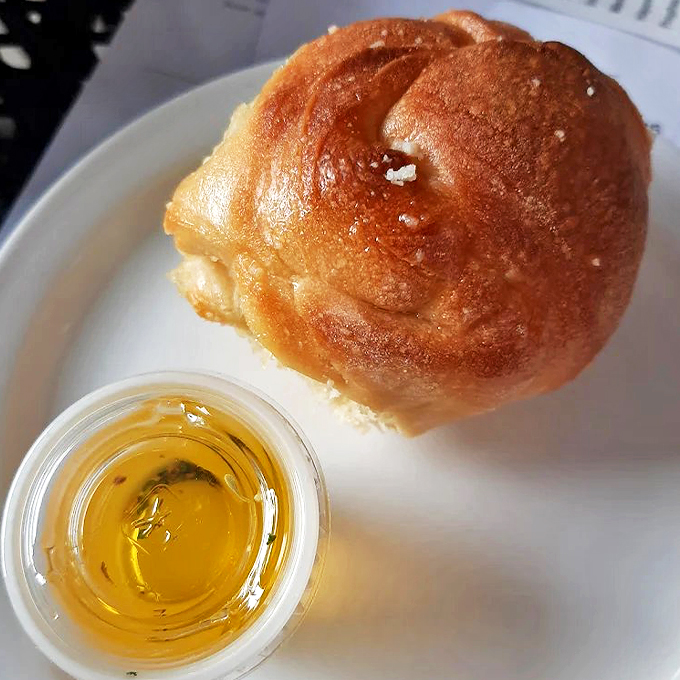 One perfect garlic knot sits beside its golden companion - olive oil - like an edible work of Renaissance art.
