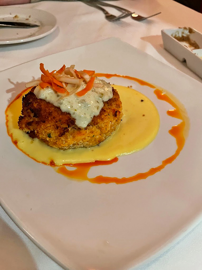 A lobster cake that's dressed to impress, with a golden crust and sauce that's doing a happy dance around the plate. 