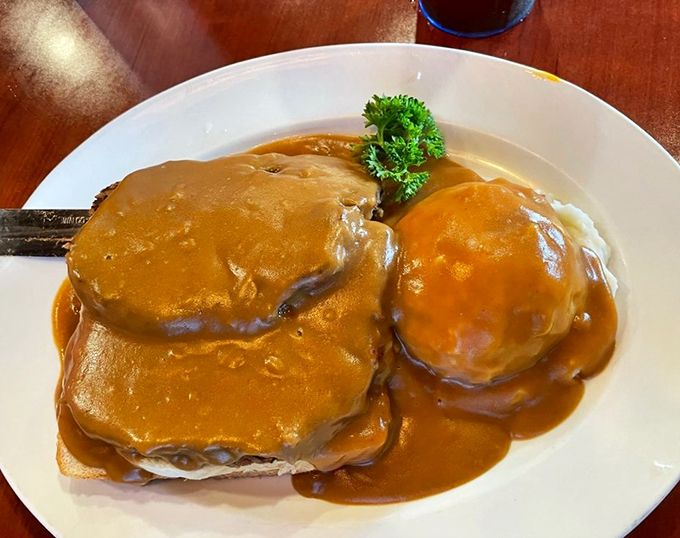 Comfort food royalty: tender meatloaf perched atop bread islands in a sea of rich, savory gravy.