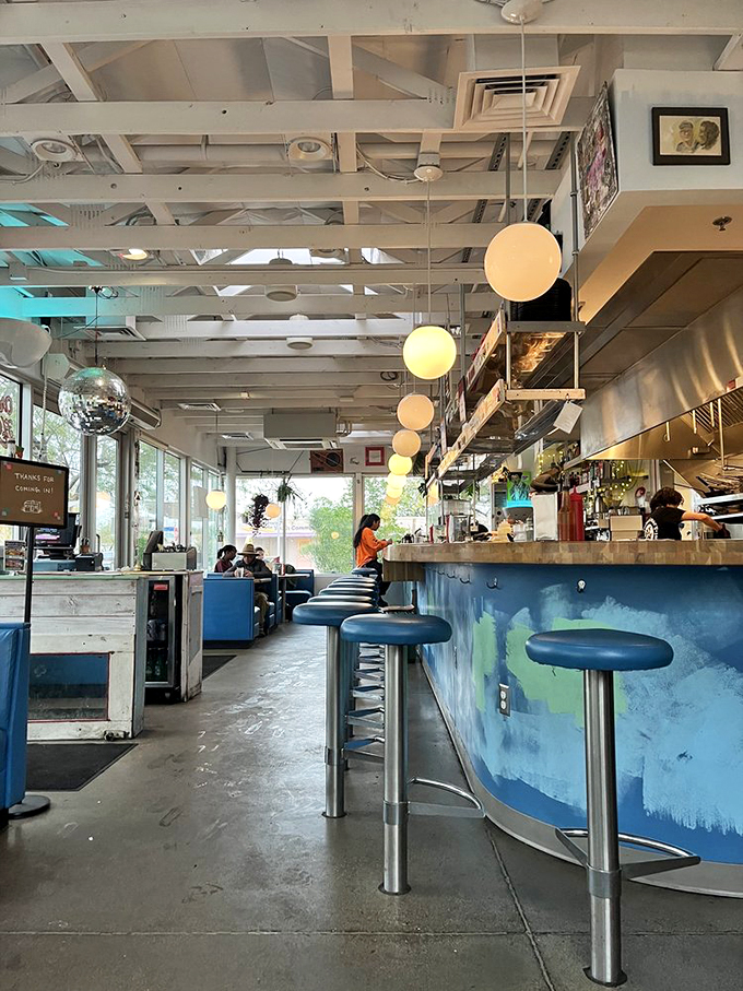 Globe lights and blue booths create an atmosphere that's part classic diner, part modern hangout spot.
