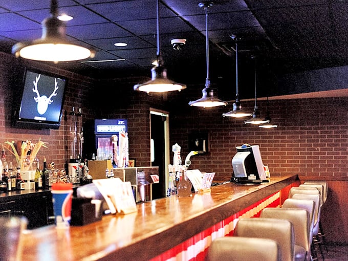Industrial pendant lights illuminate the warm wooden bar top, creating an inviting spot for post-game celebrations.