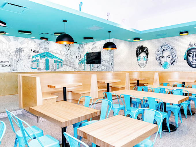 White walls adorned with playful murals and turquoise chairs create a space that feels like Miami Beach met a modern diner.