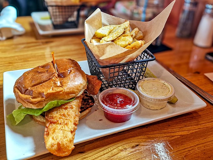 The fish sandwich arrives like a crispy crown, perched atop a golden brioche throne with seasoned fries.