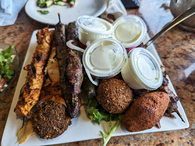 A feast fit for royalty: perfectly grilled meats share the stage with creamy hummus and vibrant pickled vegetables.