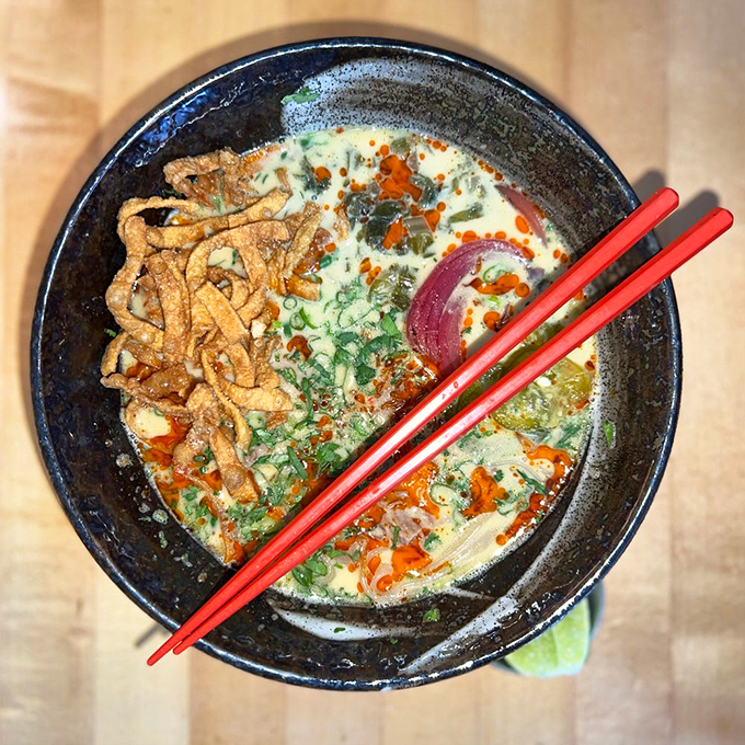 The khao soi arrives like modern art in a bowl, with crispy noodles creating a textural crown over its curry kingdom. Photo credit: Gary G.