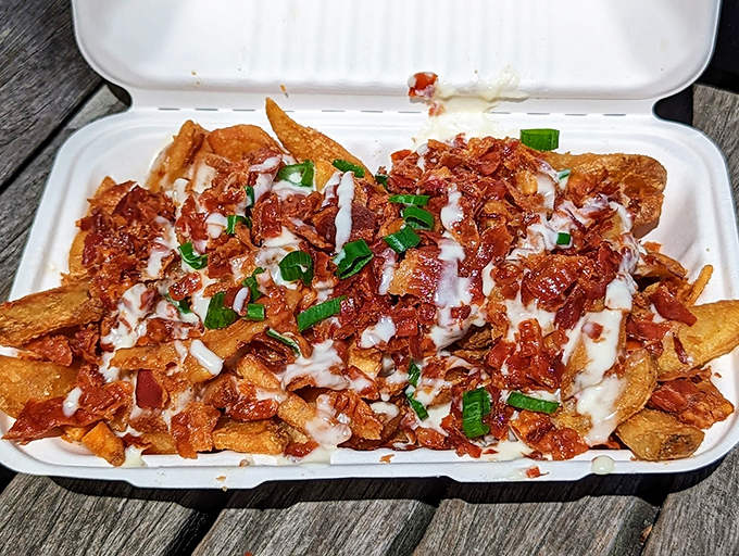 Loaded fries get dressed up with crispy bacon, scallions, and a drizzle of sauce that'll make you forget your manners.