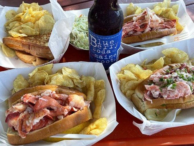 A trio of lobster rolls, each telling its own delicious story, served with a generous helping of crispy chips.