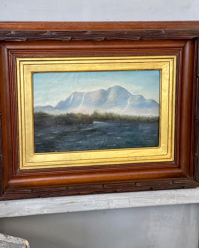 A serene landscape captures Maine's rugged beauty, framed in warm wood that's seen its share of sunsets.