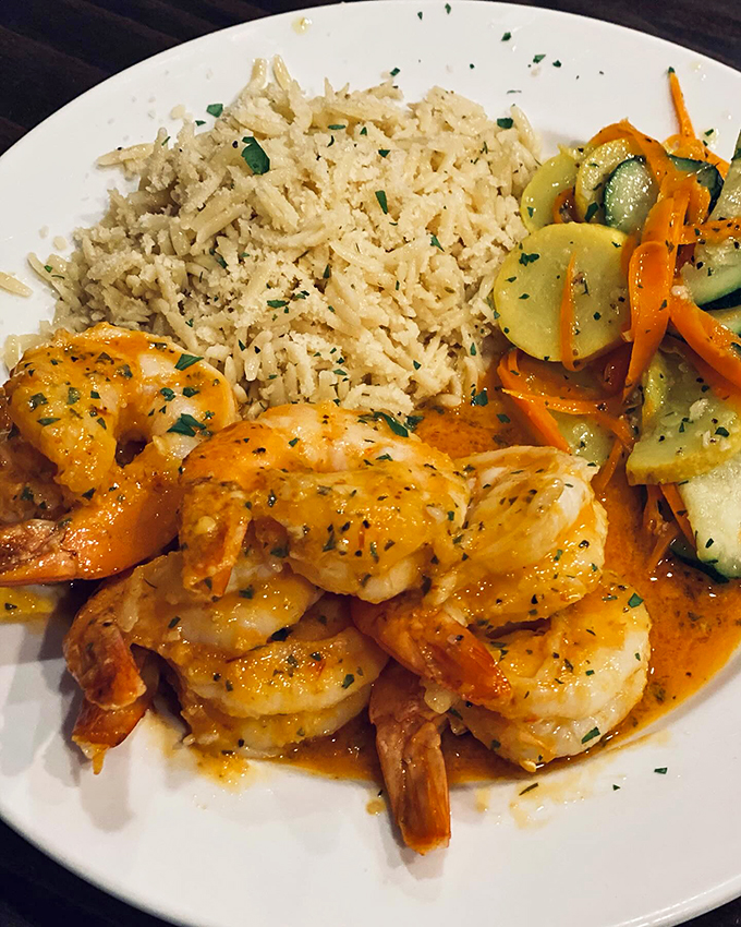 Succulent shrimp swimming in a vibrant sauce, served alongside perfectly seasoned rice and fresh vegetables - seafood perfection.
