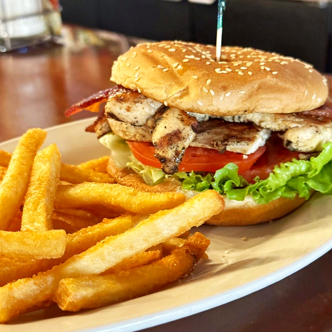 This isn't just any burger - it's a towering masterpiece of fresh lettuce, tomato, and perfectly seasoned patty. Photo credit: 5th Avenue Cafe