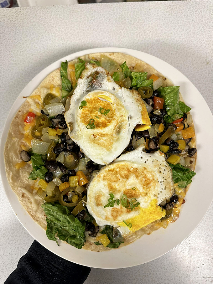 A fiesta on a plate: eggs sunny-side up reign over black beans and veggies like kings of the breakfast kingdom.