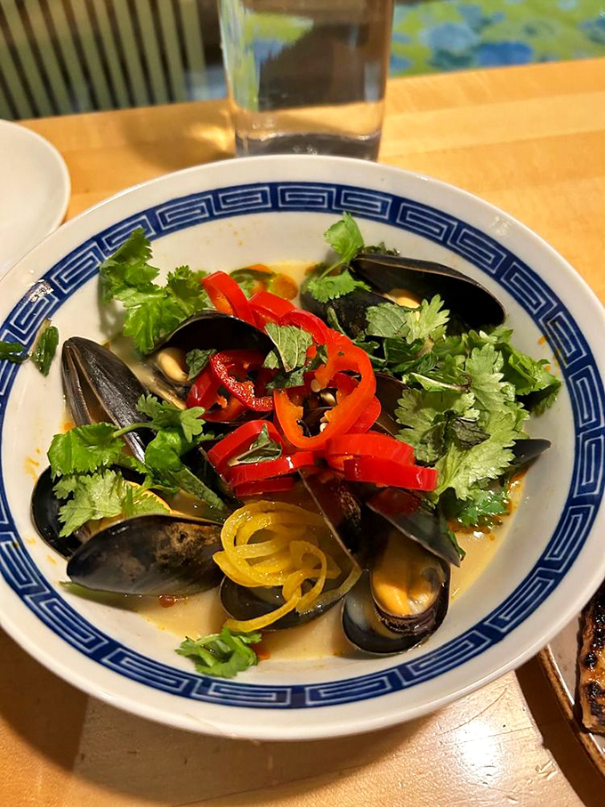 Fresh mussels bask in a fragrant broth, decorated with peppers and herbs like jewels in a seafood crown. Photo credit: James Z.