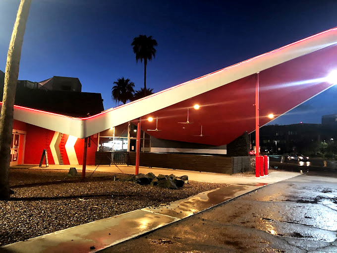 The dramatic angular roofline takes on a different personality at night, illuminated against the desert sky.