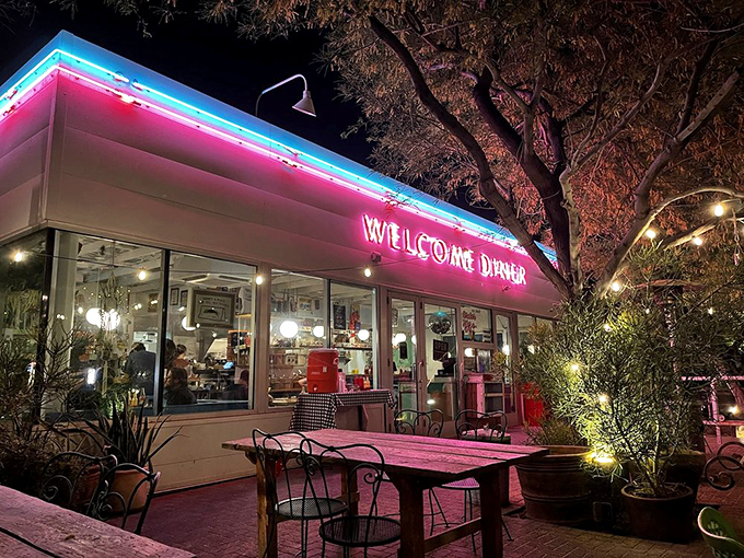 Pink neon bathes the outdoor seating in a dreamy glow that makes every meal feel like a special occasion.