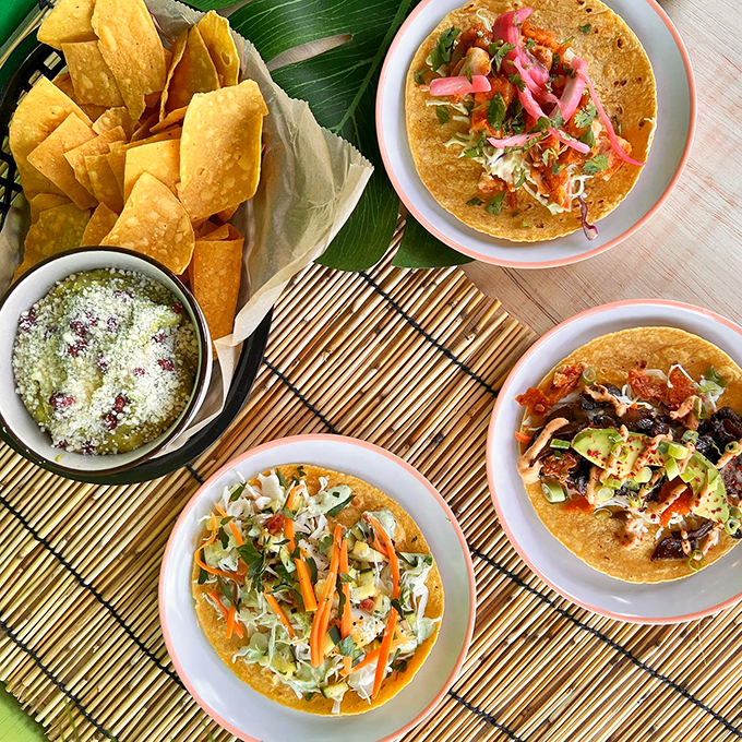 A fiesta on a bamboo mat: three different tacos telling their own delicious stories, accompanied by house-made tortilla chips.