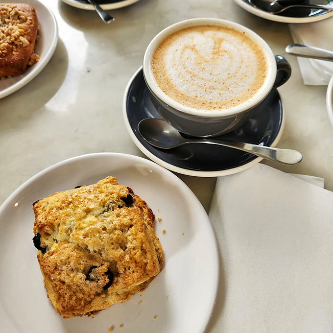 A perfectly pulled latte meets its soulmate: a blueberry scone that's ready for its close-up.