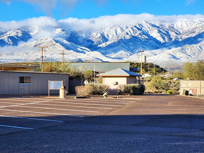 A snow-capped mountain range provides a stunning backdrop to a simple parking lot.