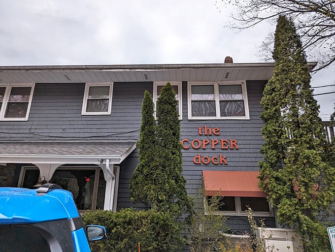 Classic lakeside charm meets mid-century modern design in this gray-shingled supper club, where evergreen sentinels stand guard.