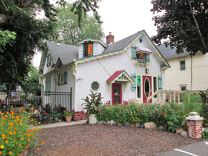 Step into a storybook! This charming white cottage, with its red-trimmed windows and inviting porch, is like a Norman Rockwell painting come to life.