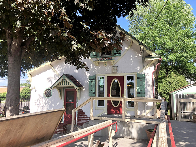 Step into a storybook! This charming white cottage, with its red-trimmed windows and inviting porch, is like a Norman Rockwell painting come to life.