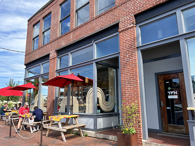 Brick and mortar meets culinary adventure! The Honey Paw's exterior promises a feast for the senses, with its inviting red umbrellas and cozy outdoor seating.