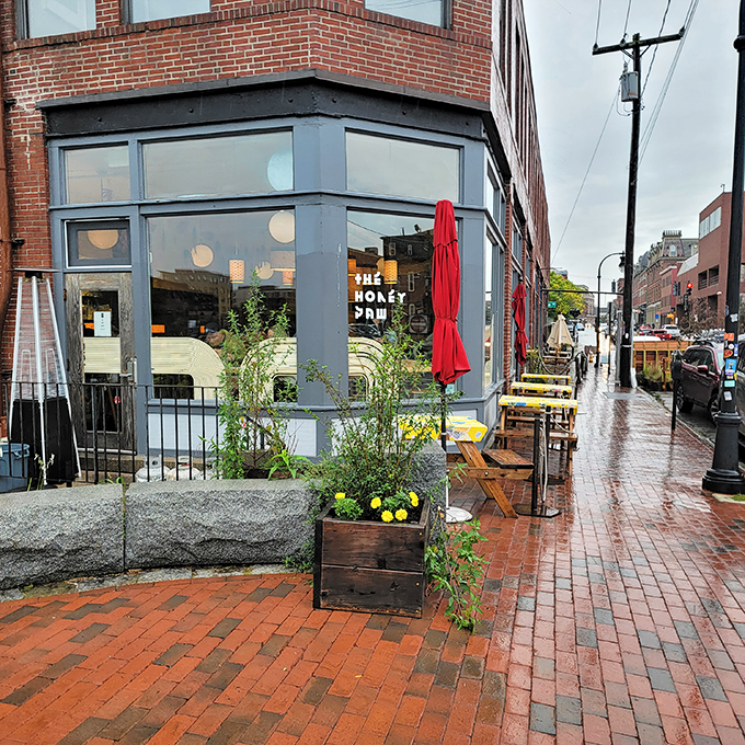 Brick and mortar meets culinary adventure! The Honey Paw's exterior promises a feast for the senses, with its inviting red umbrellas and cozy outdoor seating.