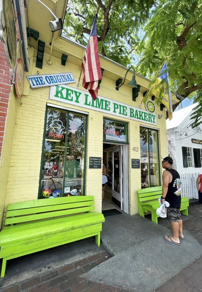 Welcome to Key West's citrus-scented paradise! The Original Key Lime Pie Bakery's cheerful yellow facade and vibrant green benches beckon like a tropical siren song.