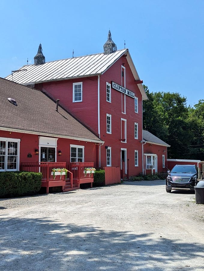 A postcard-perfect scene: Clifton Mill stands proudly, its red facade a vibrant contrast to the cascading waterfalls and lush greenery. Nature's own HGTV makeover!