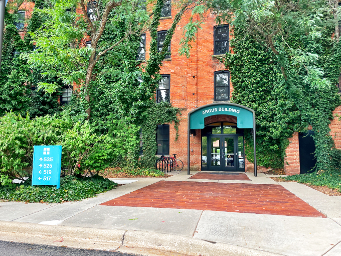 Nature's embrace! The Argus Building stands like a brick-and-ivy time capsule, inviting curious souls to step into a world where memories are frozen in film.