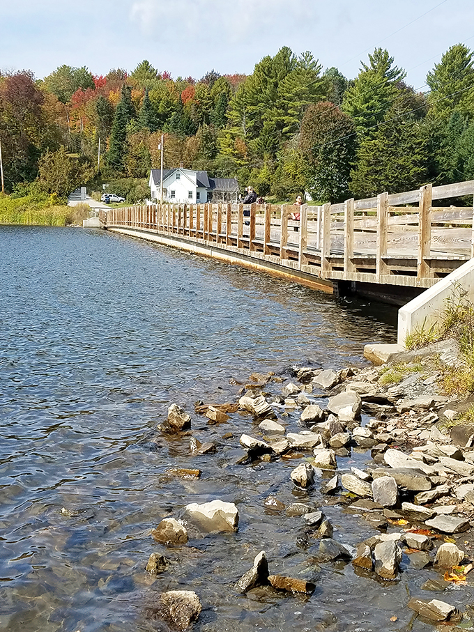 The floating bridge stretches across Sunset Lake like nature's welcome mat, complete with rustic wooden railings and autumn-painted hills.