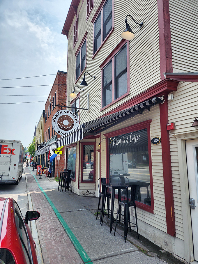 The iconic North Country Cakes sign swings like a beacon of hope for donut lovers on Morrisville's main street. Small-town charm meets serious baking.