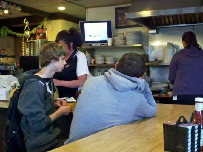 Hungry patrons at the counter, waiting for their feast. It's like watching the starting line of the Indy 500, but with forks instead of cars.