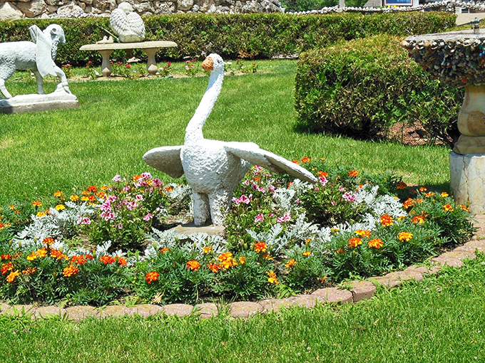 Swan lake, but make it fabulous! This stone bird is ready for its close-up, surrounded by a floral red carpet worthy of avian royalty.