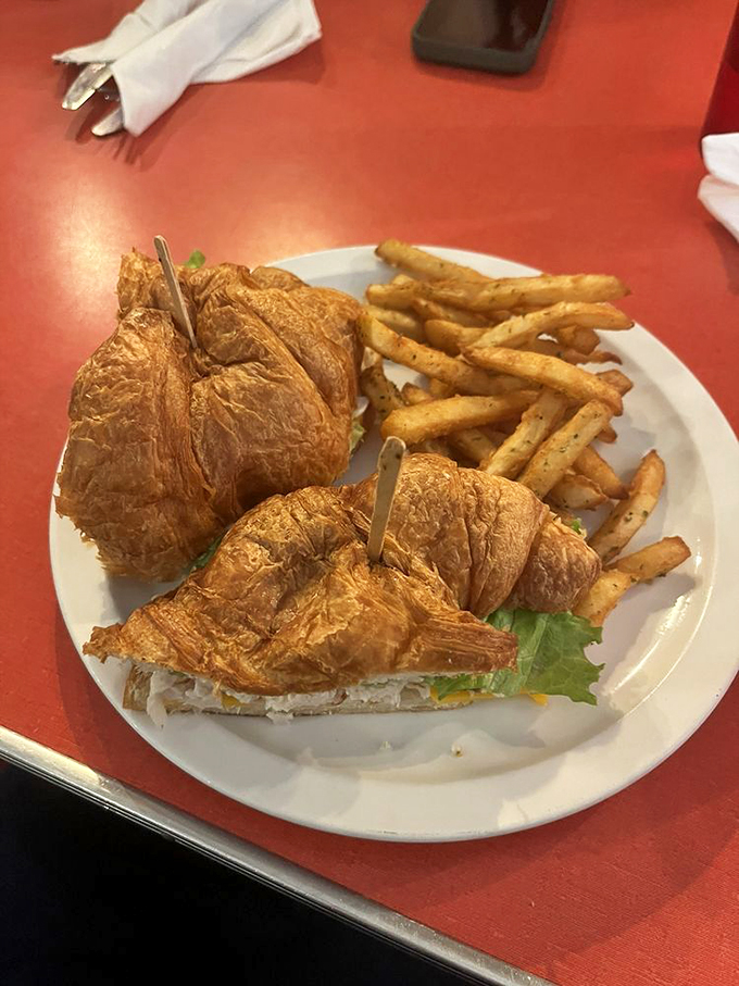 Croissant sandwich goals! This golden beauty, paired with crispy fries, is comfort food elevated to an art form.