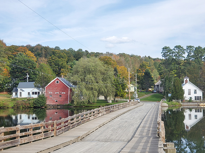 Classic white houses and a red barn frame the bridge like bookends to a Vermont story.