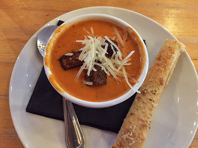 Soup's on, and it means business! This creamy concoction, topped with a blizzard of cheese, is comfort in a bowl. The breadstick stands ready, prepared for its dunking destiny.