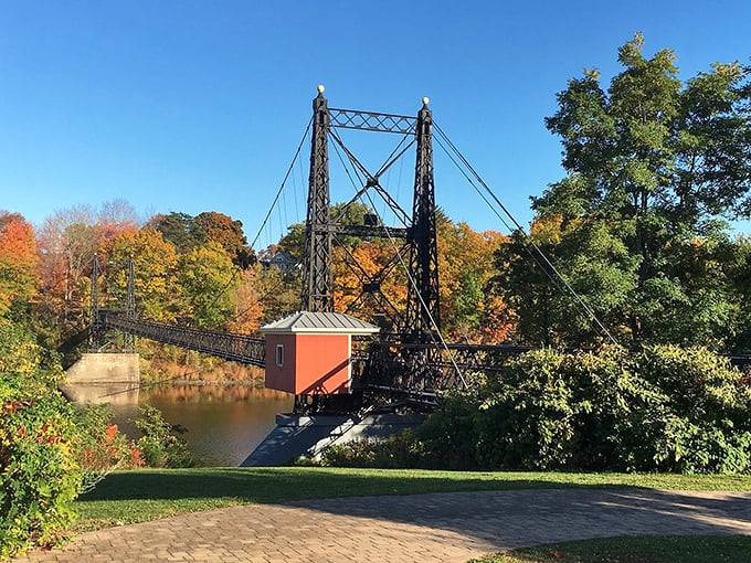 Fall's fashion show: Nature dons its autumn best, framing the bridge in a riot of reds and golds. Even the trees are dressing up for this centenarian!